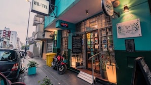 Um hotel com uma placa visível para um café, uma moto estacionada na frente e um letreiro com o número 365 na parede.