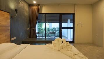 Quarto de hotel com cama, um banco e vista para o exterior, além de uma porta de correr.