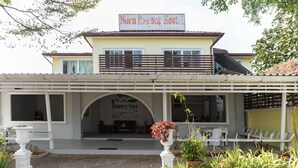 Um edifício de dois andares com uma placa que diz 'Norn Borneo Hostel'.