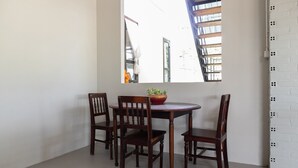 Uma área de refeições com uma mesa redonda e quatro cadeiras de madeira. Há uma tigela com uma planta sobre a mesa.