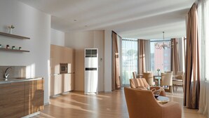 Cozinha moderna com micro-ondas embutido e geladeira, área de jantar com lustre e janelas amplas com cortinas.