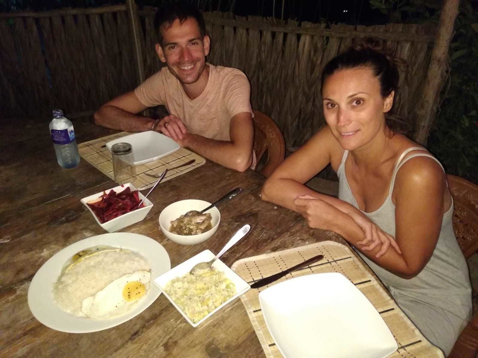 Uma mesa de jantar de madeira com pratos de comida, uma garrafa de água e uma faca.