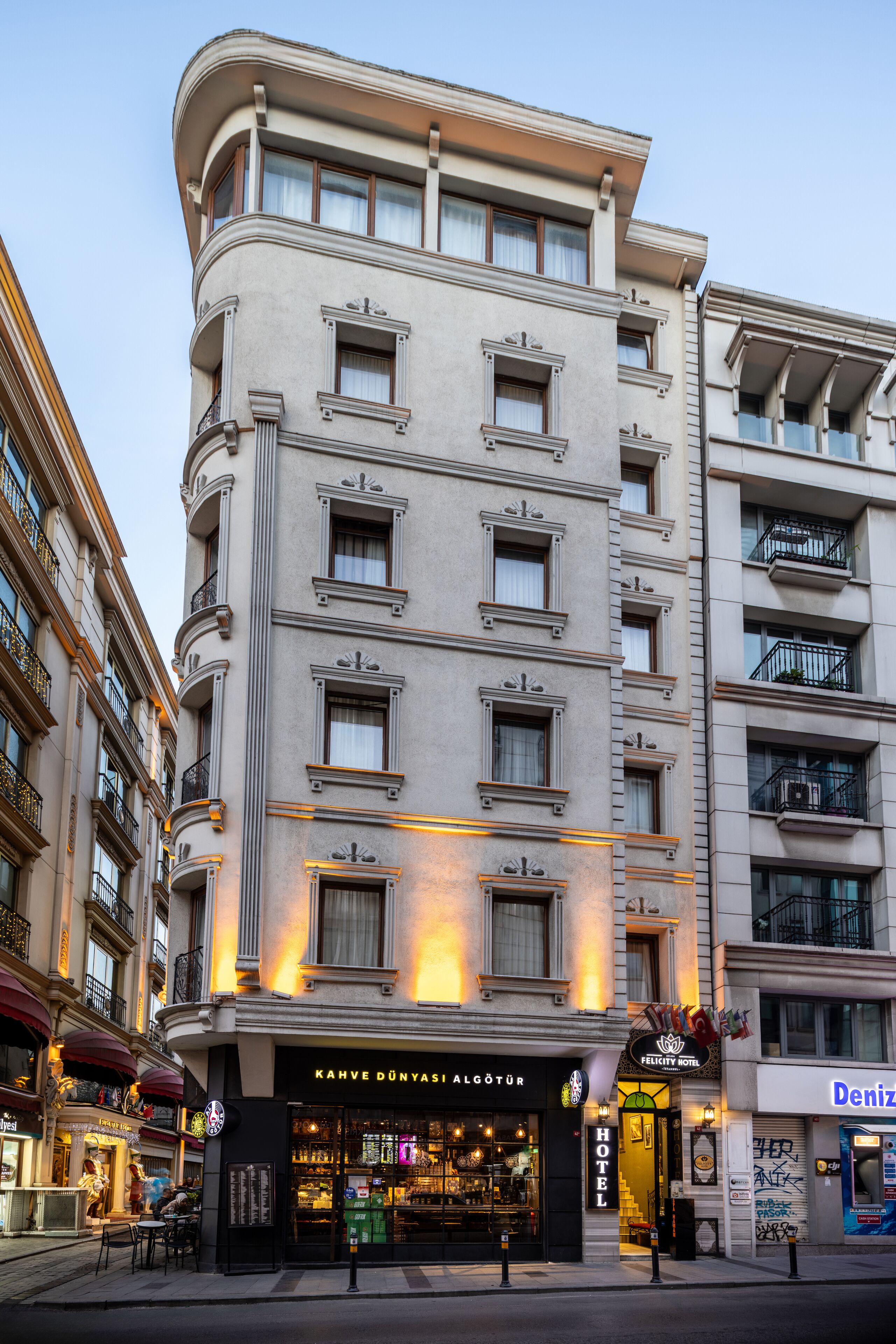 Um hotel de vários andares com estilo arquitetônico clássico, com uma loja no andar térreo e entrada visível.