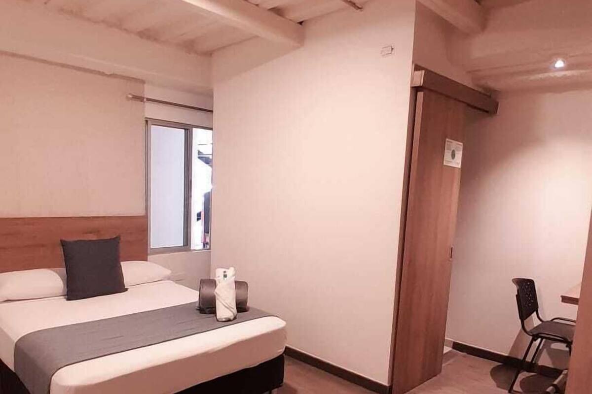 Quarto de hotel com cama, escrivaninha e cadeira.