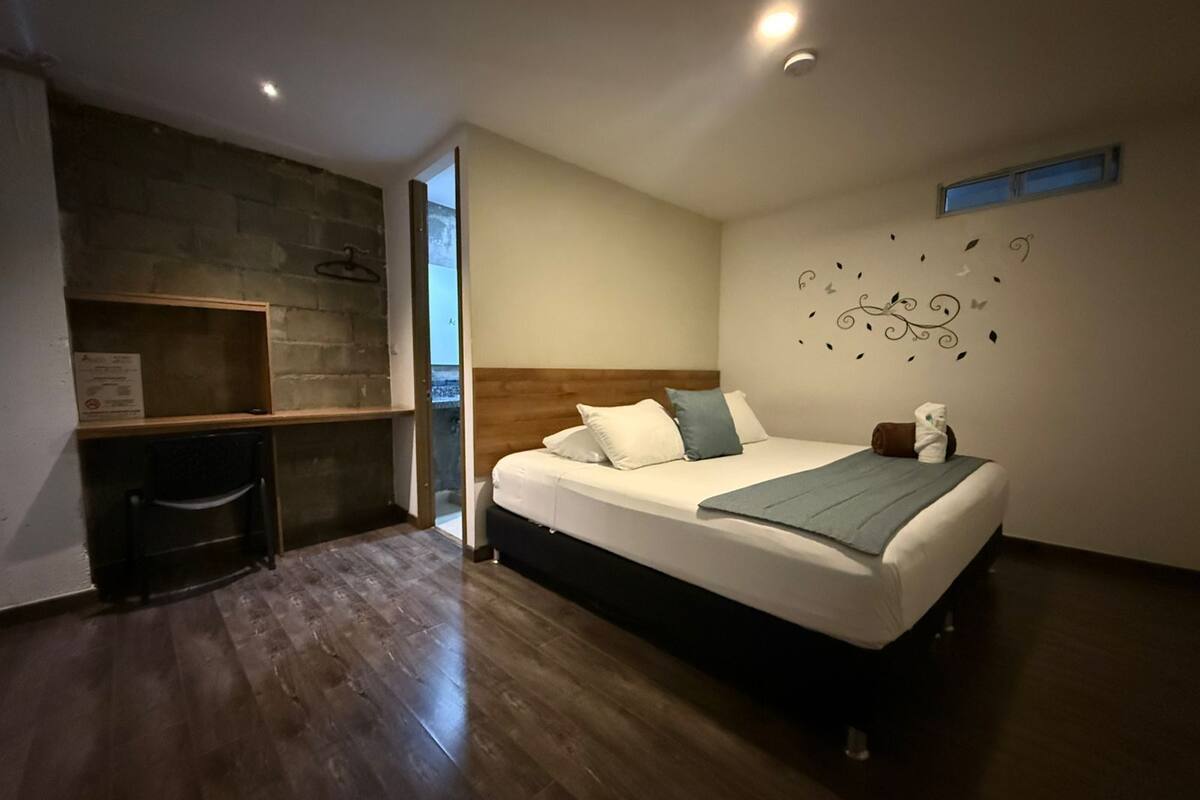 Quarto com cama, escrivaninha de madeira, parede de pedra e um decalque decorativo.