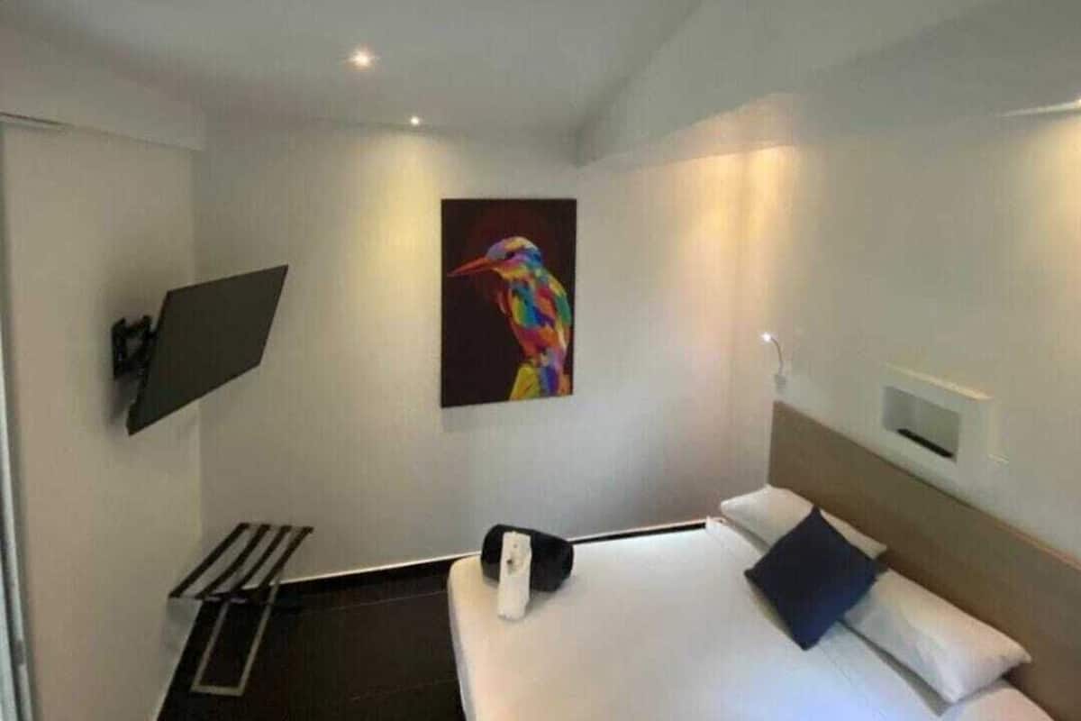 Quarto de hotel moderno com cama, quadro, escrivaninha e cadeira.