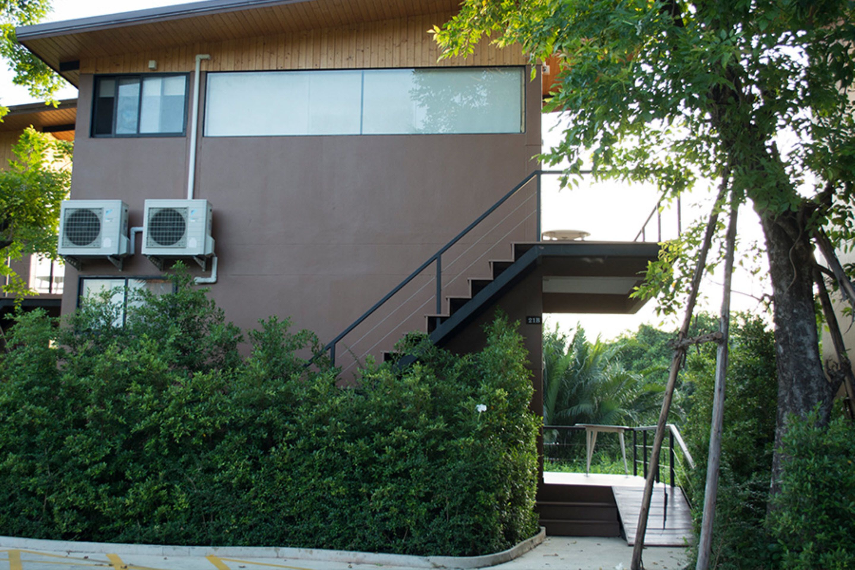 Um edifício moderno com duas unidades de ar condicionado, uma escadaria e um pequeno terraço ao ar livre.