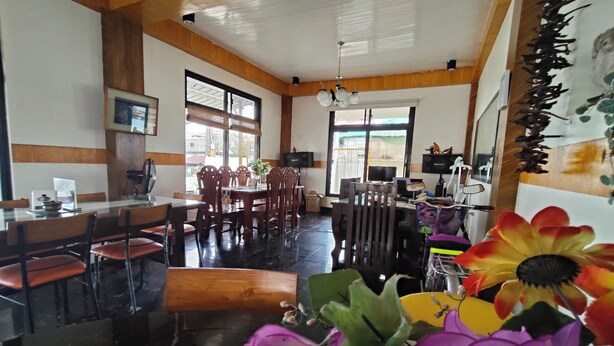 Uma sala de jantar com mobiliário de madeira, uma janela grande e um quadro na parede.