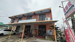 Um edifício de dois andares com telhado plano, varanda frontal coberta e uma placa anunciando um restaurante.
