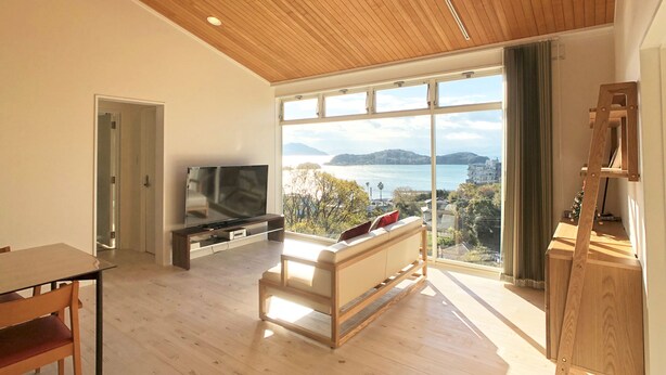 Uma sala de estar moderna com uma janela grande, uma TV de tela plana e teto de madeira.
