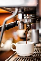 Máquina de café servindo café numa chávena branca.