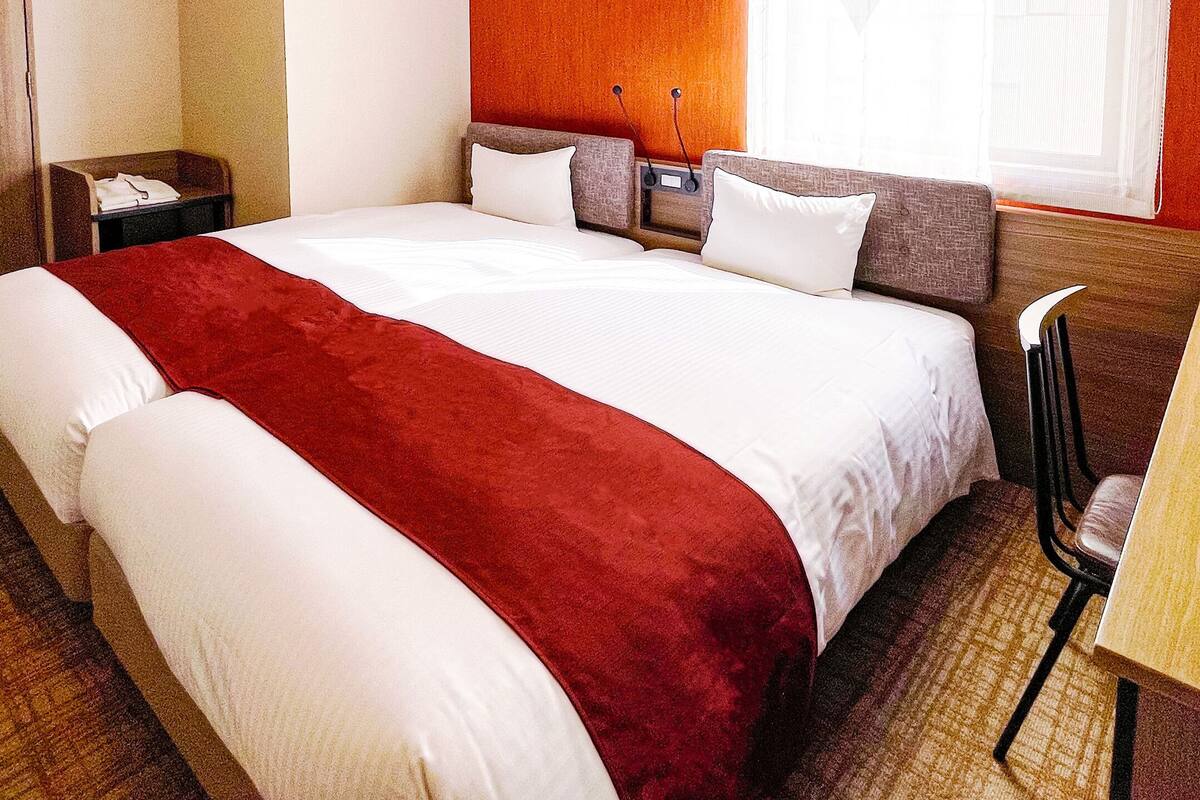 Quarto de hotel com uma cama grande, uma mesa de cabeceira, uma cadeira e uma janela.