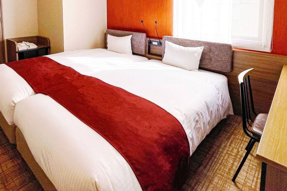 Quarto de hotel com uma cama grande, uma escrivaninha e uma cadeira.