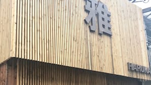 Fachada de edifício com ripas verticais de madeira e um grande letreiro com caracteres chineses.