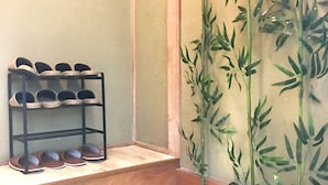 Um canto com um sapateiro, um banco de madeira e uma planta de bambu.