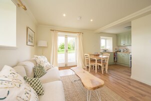 Uma sala de estar ampla com um sofá, um banco de madeira e um espaço de jantar com cadeiras e uma mesa.