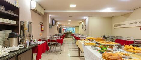 Disposição de buffet com diversos tipos de comida, um espaço para café e um extintor de incêndio na parede.