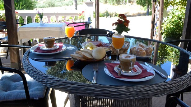 Mesa posta para o café da manhã com diversos alimentos e bebidas.