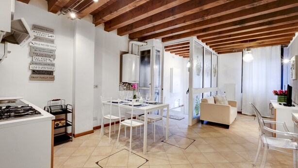 Cozinha moderna com fogão a gás, armários brancos e uma área de refeições com mesa e cadeiras brancas.