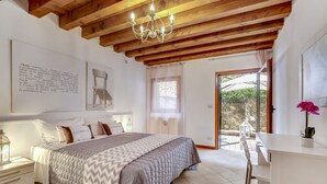 Quarto com cama, mesa de cabeceira e área de estudo.