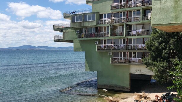 Um edifício com várias andares e varandas com vista para a praia.