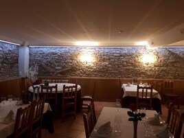Um restaurante com paredes de pedra, mesas e cadeiras de madeira.