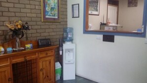 Uma área de recepção com uma mesa de madeira, um bebedouro e um espelho.