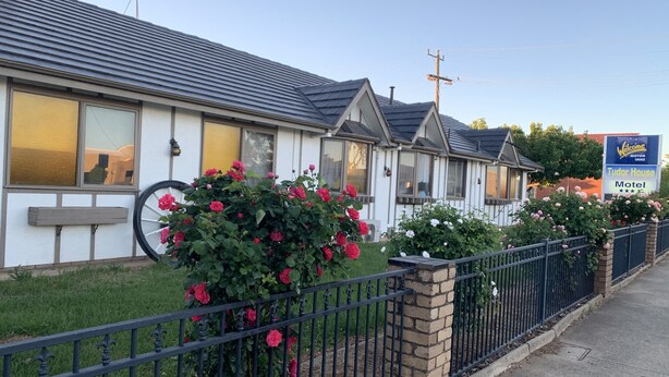 Um motel com uma fileira de edifícios térreos, cada um com telhado escuro e janelas grandes.