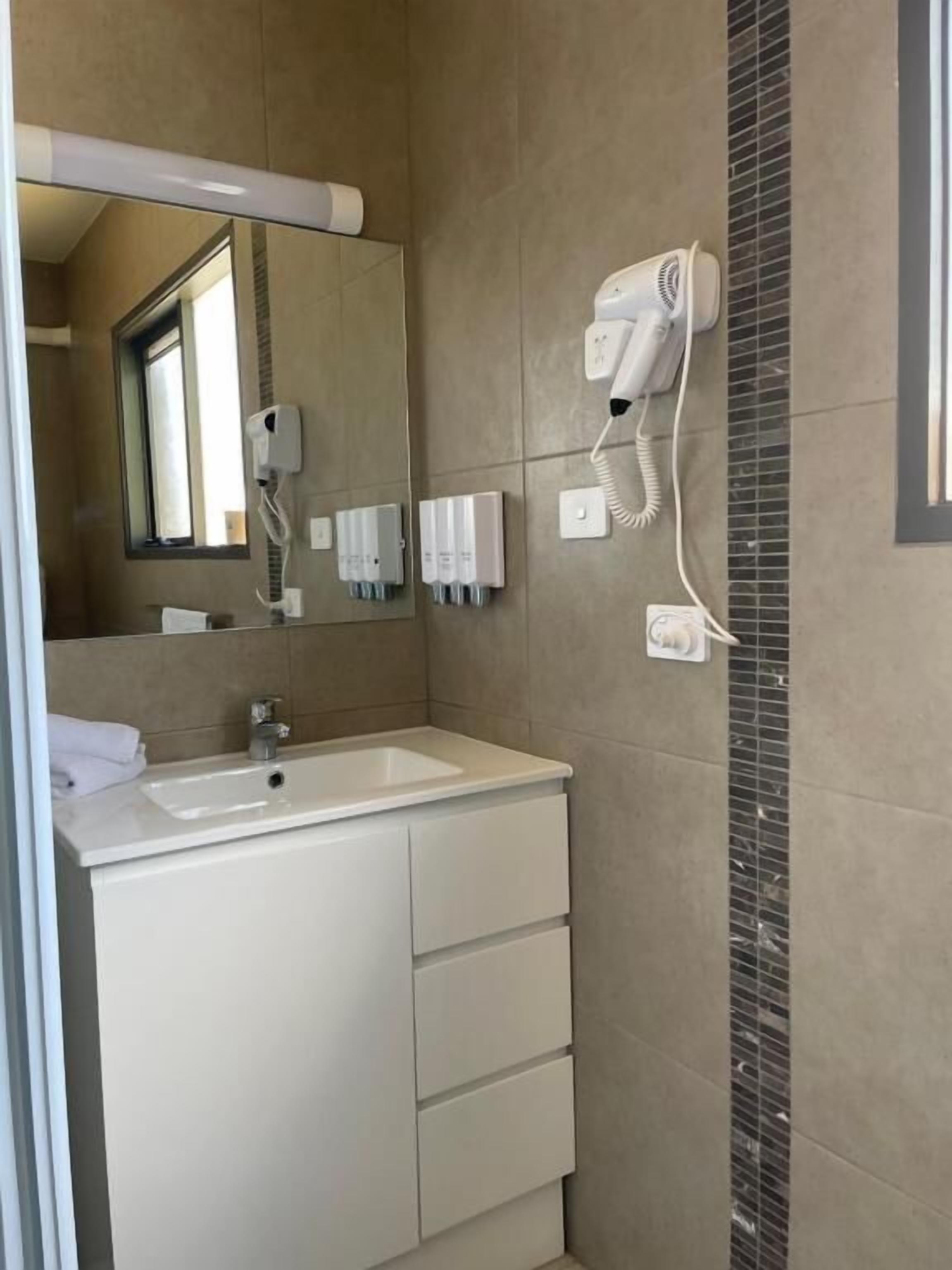 Casa de banho com lavatório, espelho, secador de cabelo e toalheiro.
