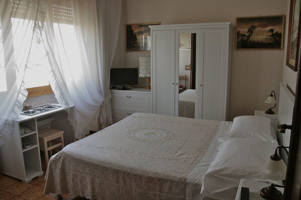 Quarto com cama, escrivaninha, guarda-roupa e mesa de cabeceira.