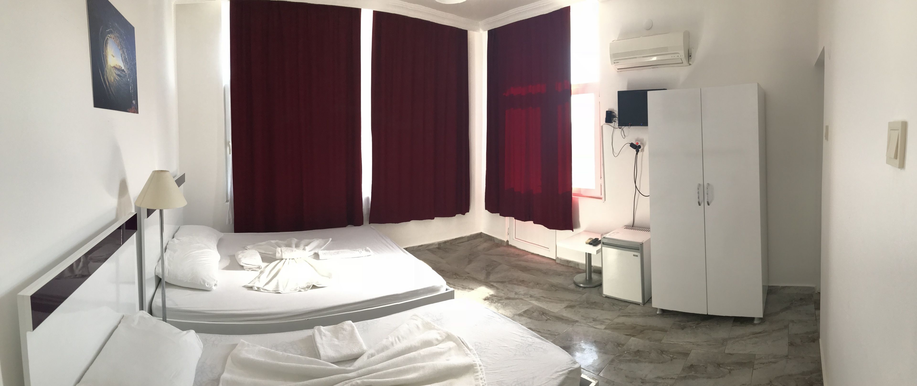 Quarto de hotel com cama, escrivaninha, armário e banheiro.