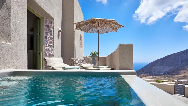 Uma piscina infinita moderna com vista clara do oceano e paisagem montanhosa.
