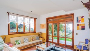Uma sala de estar ampla com sofá, mesa de centro e uma grande janela com vista para o verde.