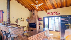 Uma cozinha com forno de tijolos, teto de madeira e banquetas.