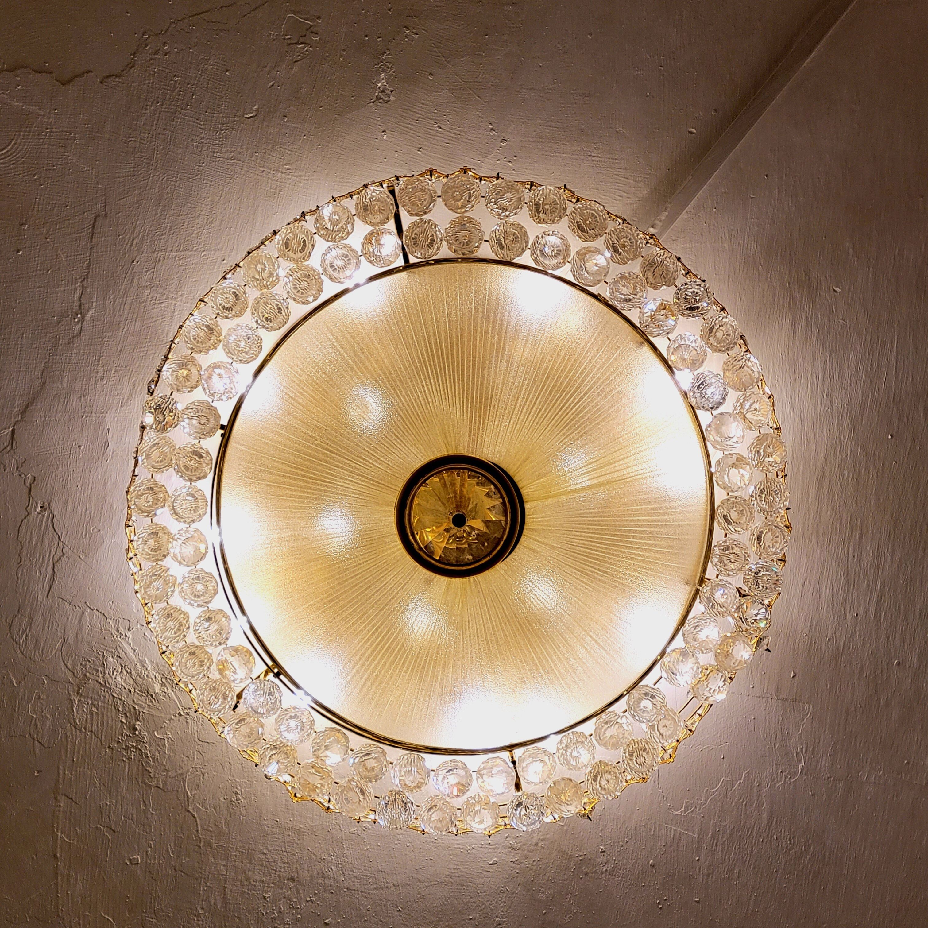 Teto com luminária circular rodeada por decorações semelhantes a cristais.