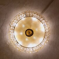 Teto com luminária circular rodeada por decorações semelhantes a cristais.