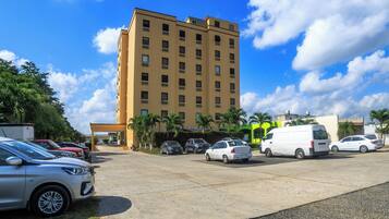 Um estacionamento com vários carros e um edifício ao fundo.