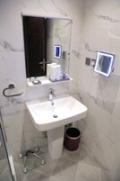 Uma casa de banho moderna com uma pia de mármore branco, um espelho em cima e zona de duche.