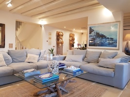Uma sala de estar moderna com um sofá seccional, uma mesa de centro de vidro e um quadro na parede.