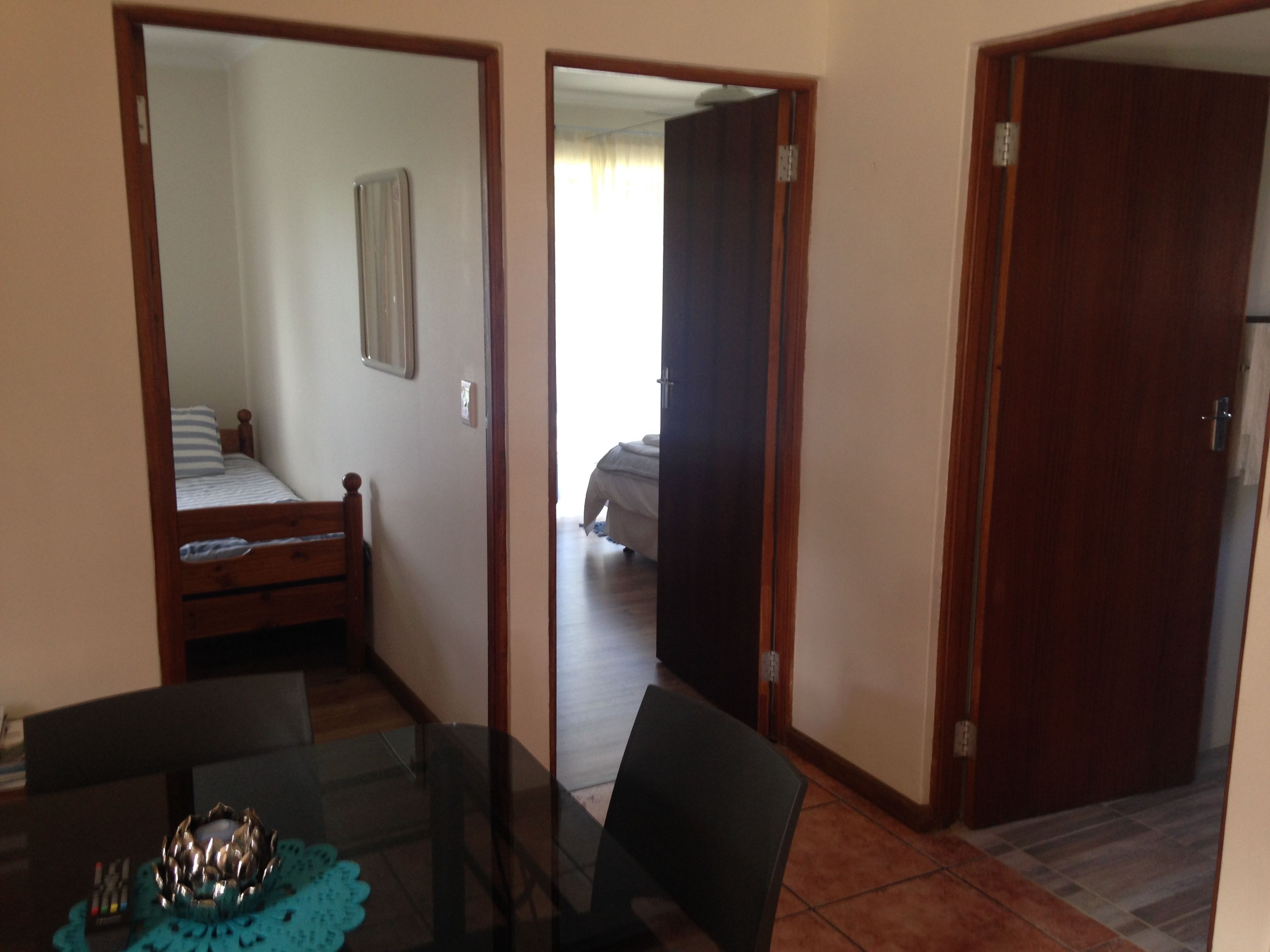 Um quarto com uma cama, uma mesa com cadeiras e uma porta que dá para outro aposento.