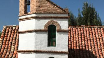 Um edifício com uma torre de sino, uma pequena janela em arco e uma porta verde.