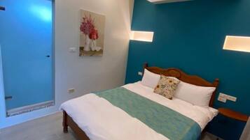 Um quarto com cama, uma pintura e parede azul.