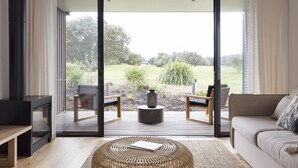 Sala de estar moderna com uma grande porta de vidro deslizante que dá para um deck, um sofá, uma mesa de centro e uma lareira.