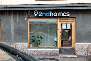 Fachada com uma grande janela de vidro, uma porta de madeira e uma placa com a inscrição '2ndhomes'.