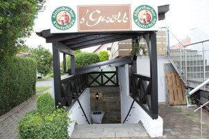 Uma escadaria leva a um edifício com uma placa que diz 'Alpersbacher Kloisterbrau'.