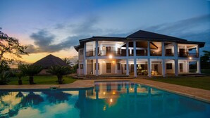 Uma casa de dois andares com piscina em frente.