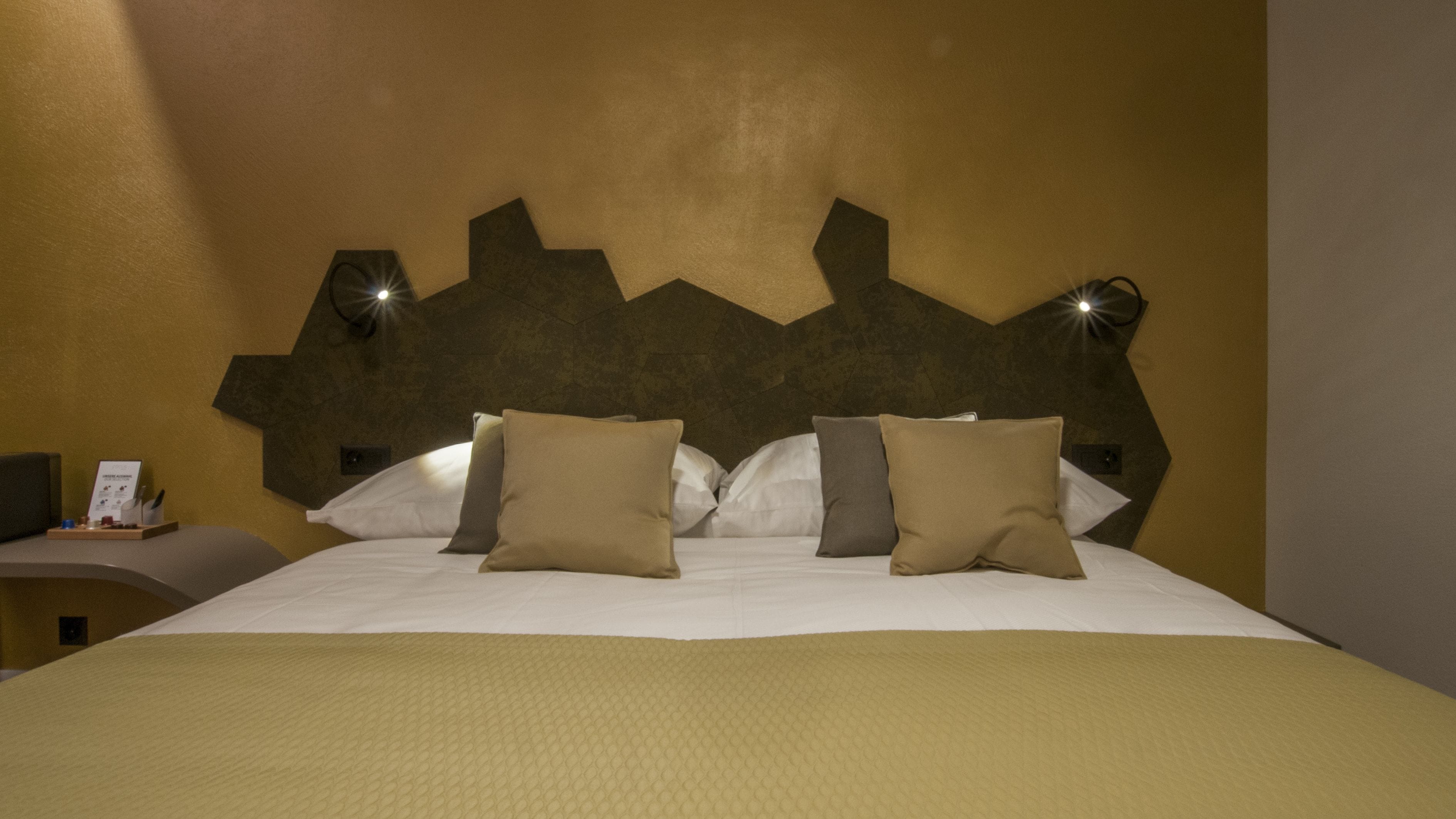 Quarto de hotel com uma cama grande, duas mesas de cabeceira e cabeceira com iluminação integrada.