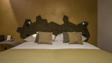 Quarto de hotel com uma cama grande, duas mesas de cabeceira e cabeceira com iluminação integrada.
