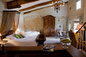 Quarto com cama, mesa de madeira, lustre, armário de madeira e banheiro com banheira.