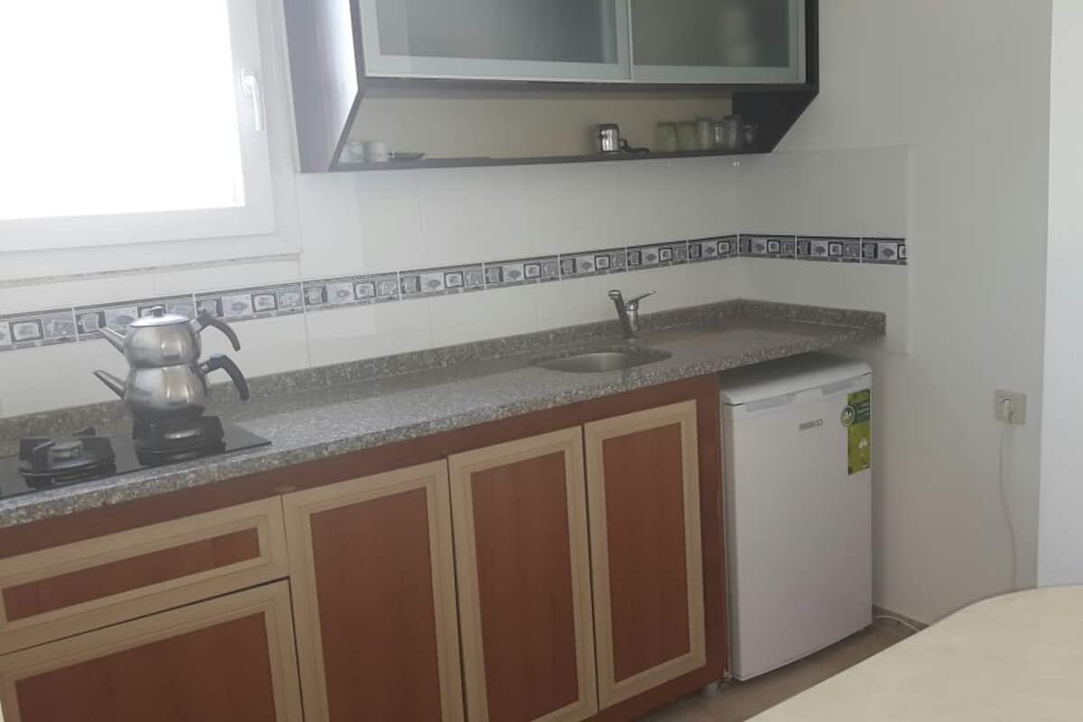 Uma cozinha com armários de madeira, geladeira branca, pia e chaleira sobre o balcão.